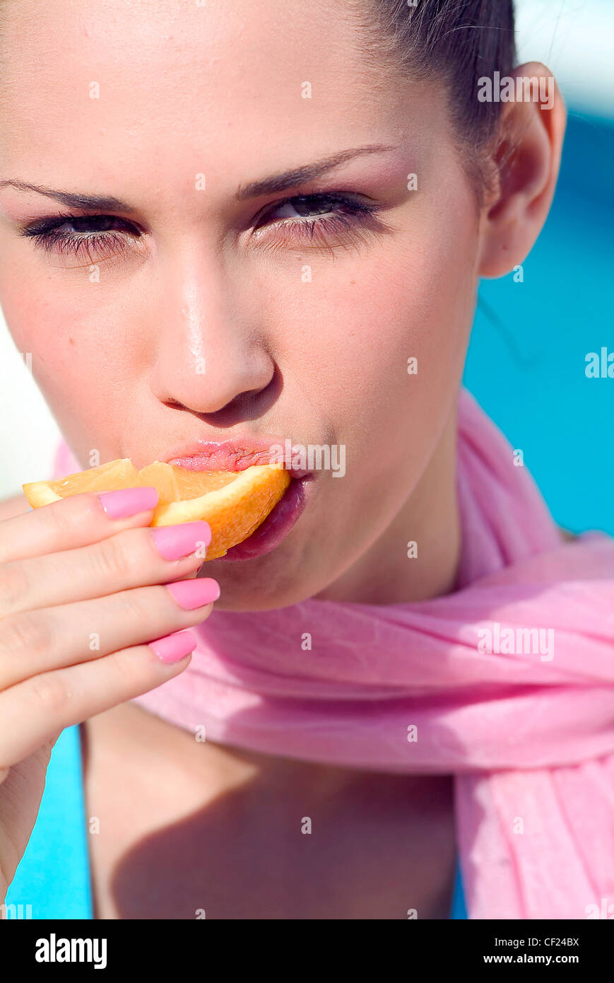 Brunette female with hair scraped back, wearing a pink scarf and biting ...
