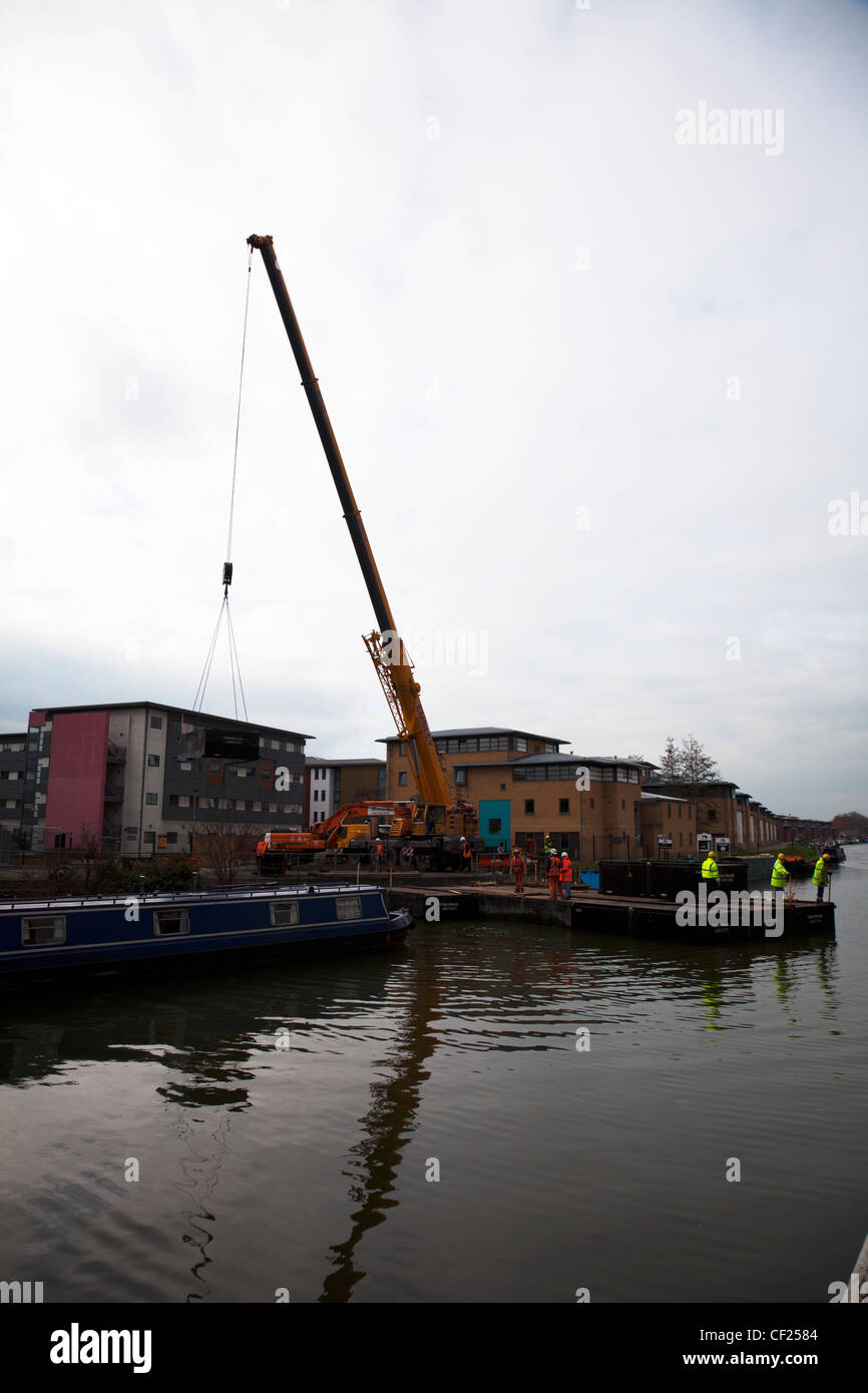 High rise tower crane lifting large floating blocks on river Witham in ...