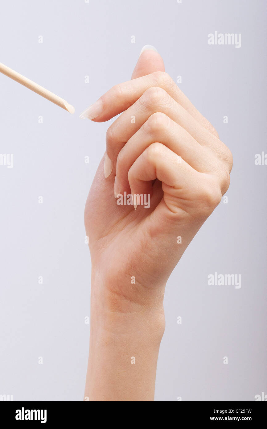 Female hand, clenched, holding orange stick to fingernail Stock Photo ...