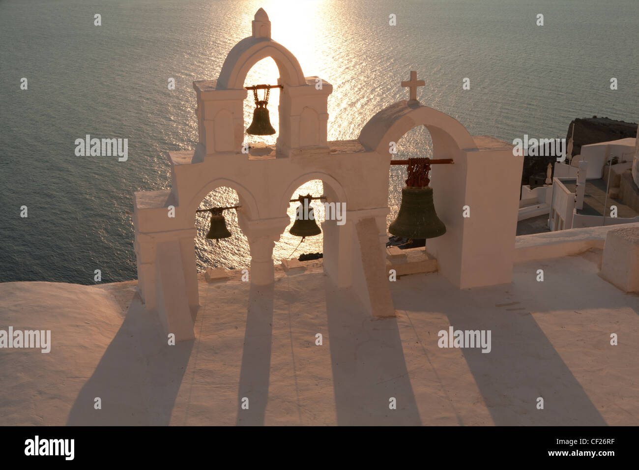 A view of a traditional bell tower at sunset with the caldera and sea ...