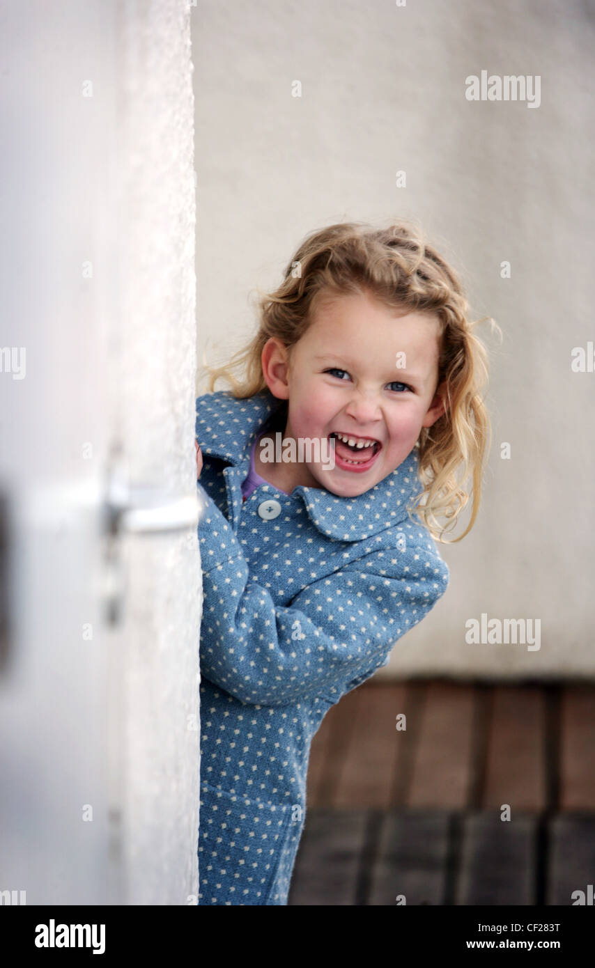 Female child peeking out from behind wall on pier at Cromer in Norfolk ...