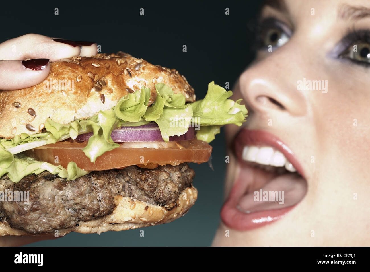 Female biting into a beef burger Stock Photo - Alamy