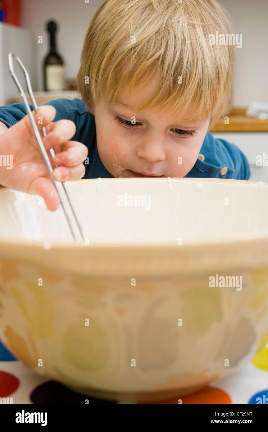 A male child eating cake mix out of a bowl Stock Photo - Alamy