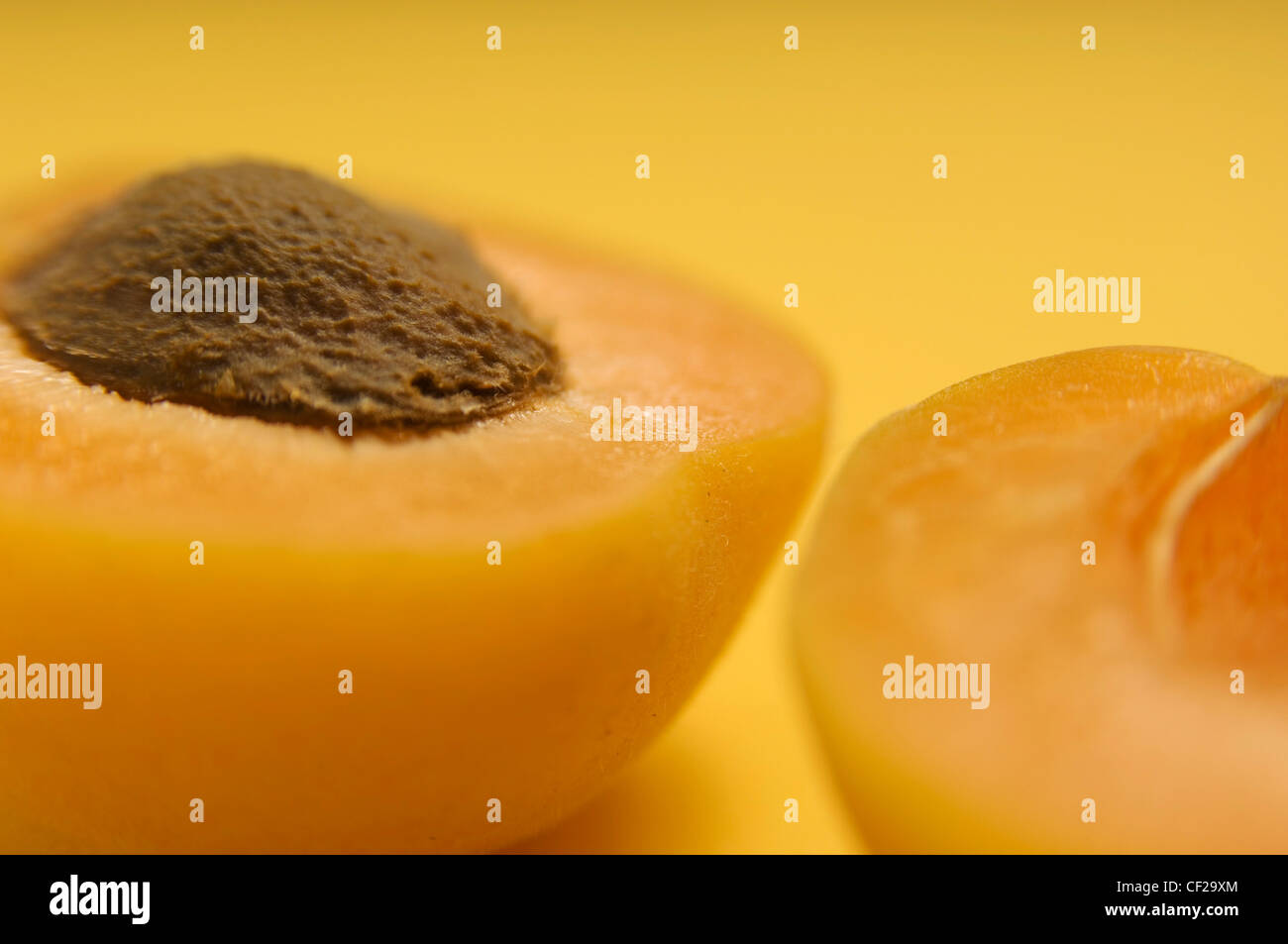 Apricot cut in half on a yellow background Stock Photo - Alamy