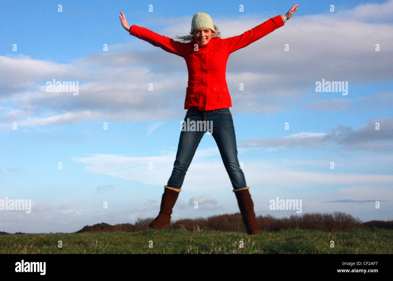 Female wearing a bright red jacket, blue denim jeans and beige knitted ...
