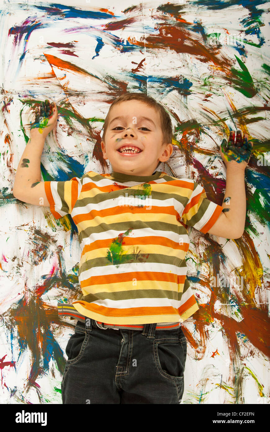 Happy messy boy lying down on painted paper background isolated on ...