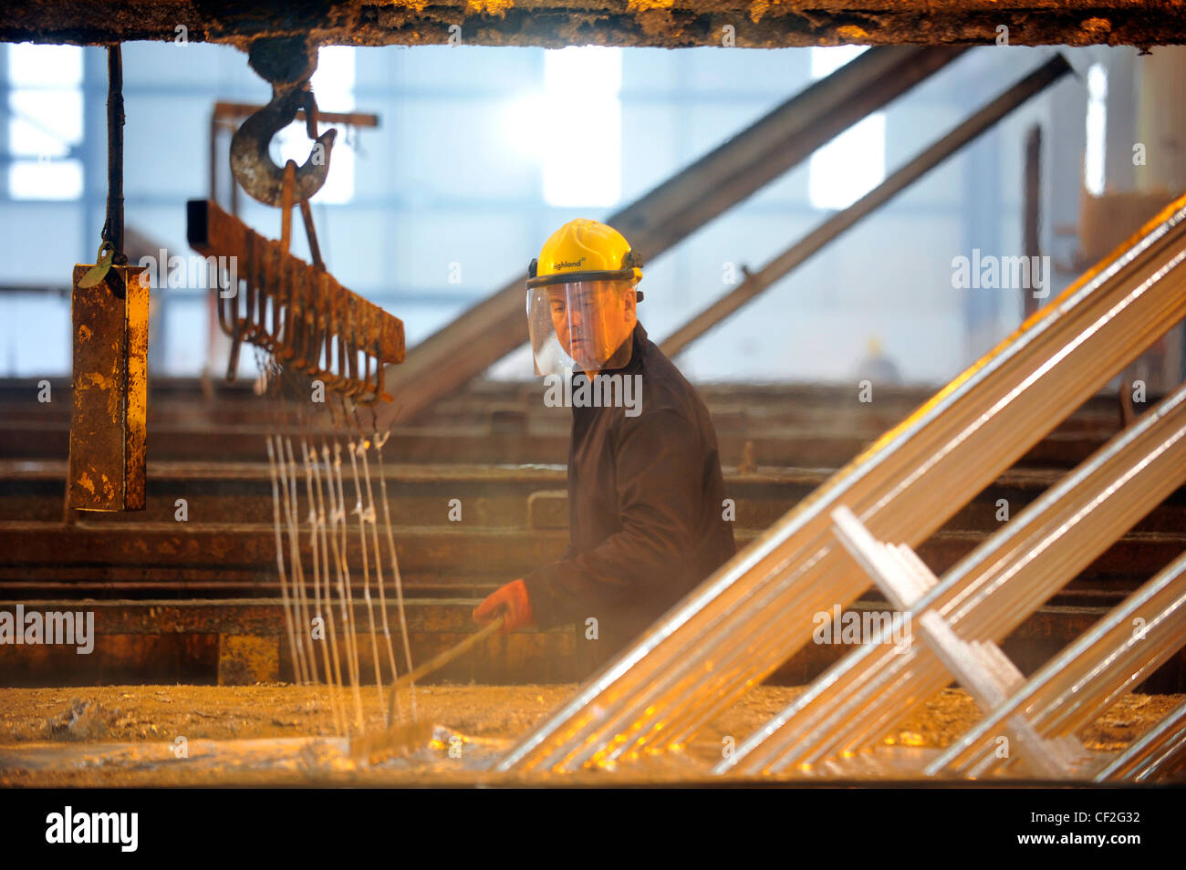 A worker prepares steel and skims molten zinc at a galvanizing plant ...