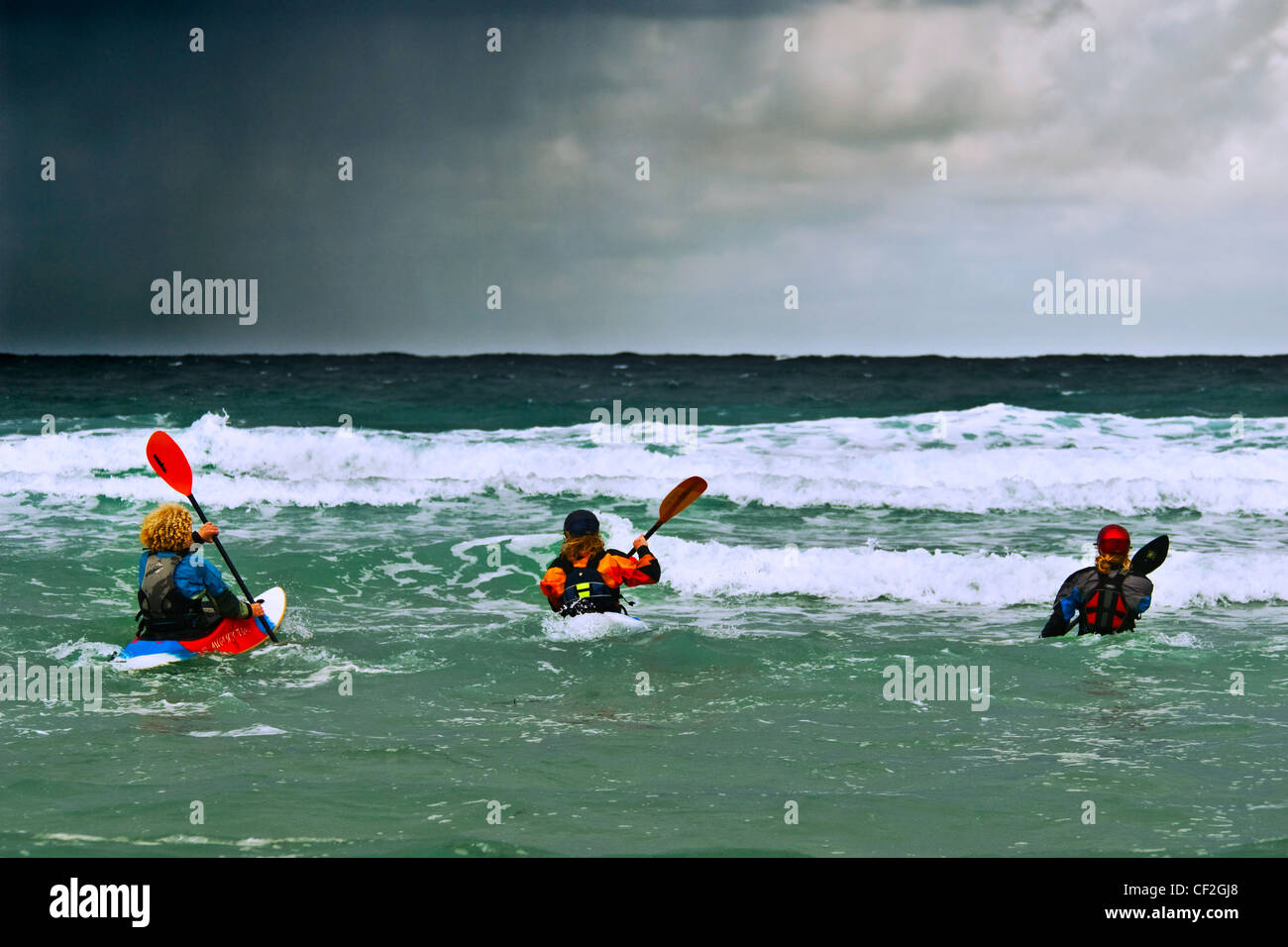 Three surf kayakers paddling out to sea as bad weather approaches at ...
