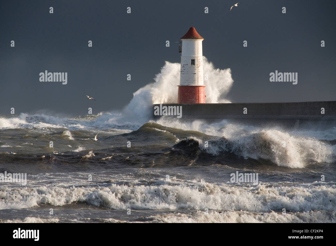 Large waves crashing around Berwick Lighthouse at the end of the pier ...