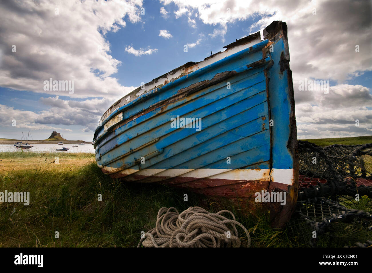 An old fishing boat on Holy Island with Lindisfarne Castle, built by ...