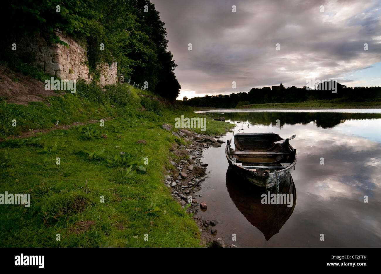 A wooden rowing boat moored on the River Tweed by Norham Castle, one of ...