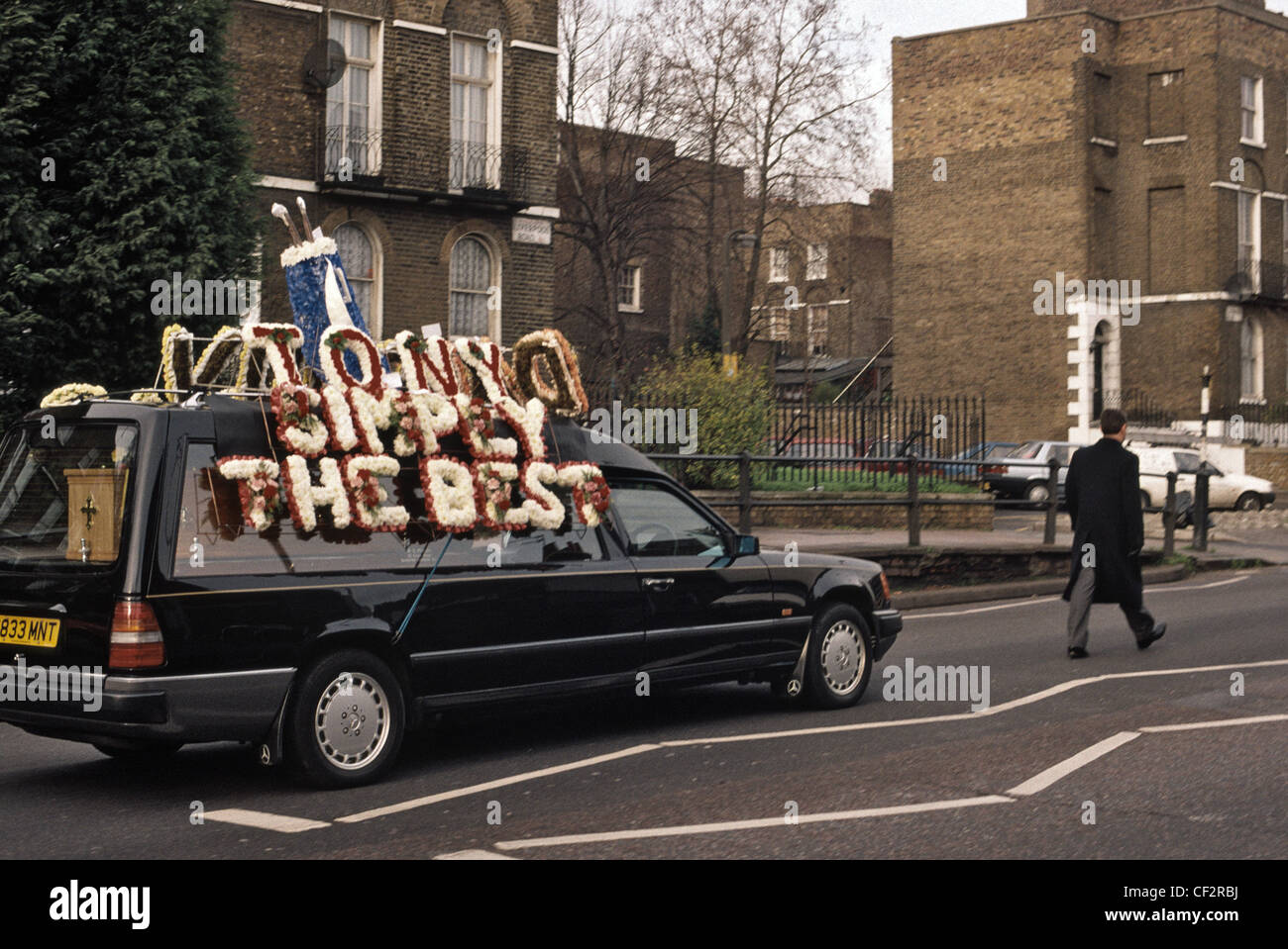Hearse driving slowly with funeral undertaker leading the procession ...