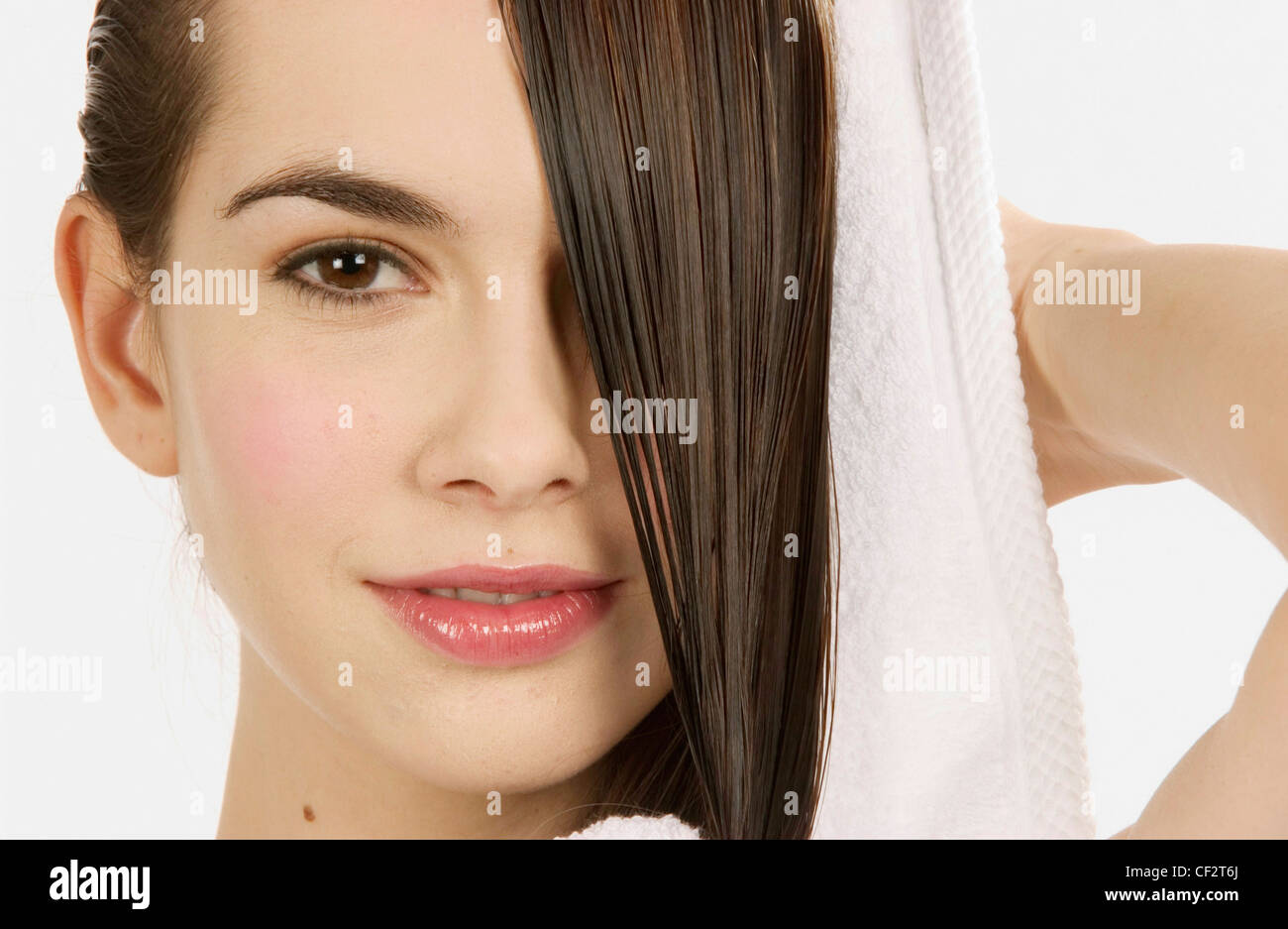 Female With Long Brunette Hair Brushed Over One Eye Rubbing It With White Towel Looking To