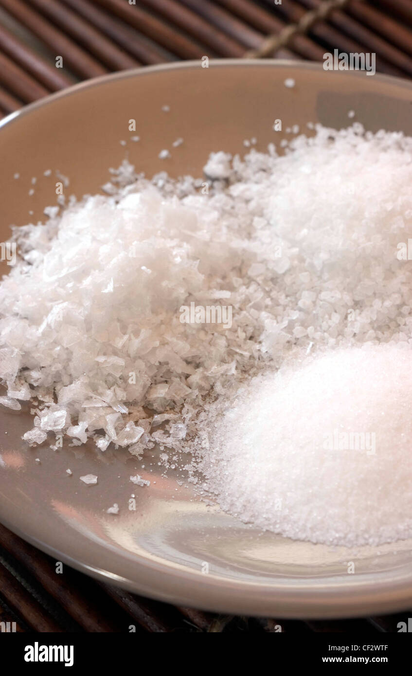 Cream plate with piles of sea salt, malden salt and table salt on ...