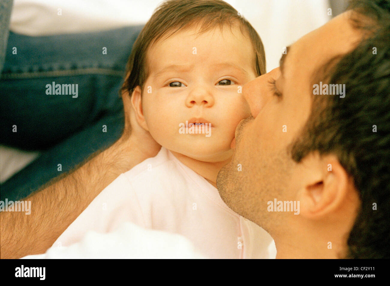 Male with dark brown hair kissing and holding baby with dark brown hair ...