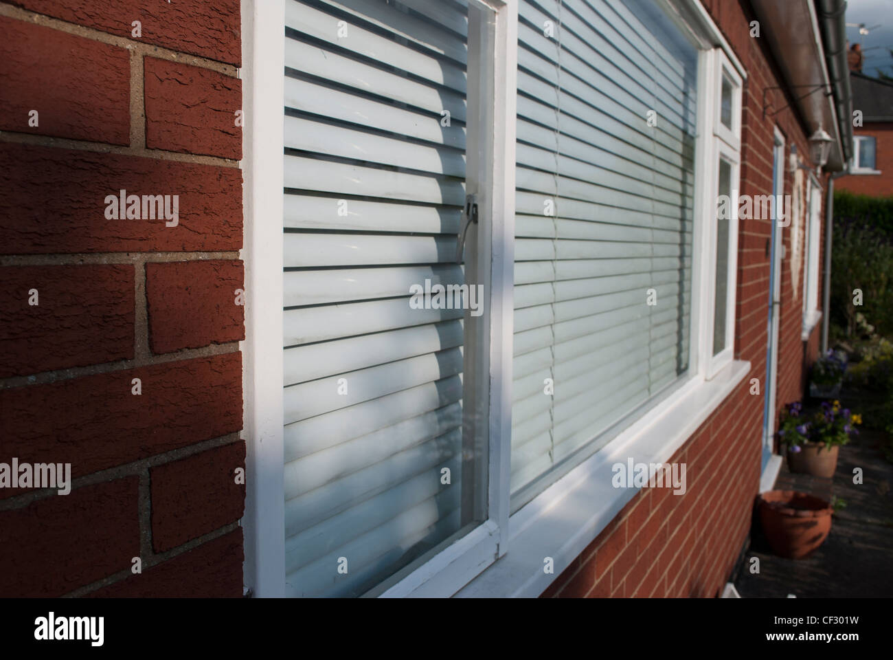 White framed window with white blind in brick wall at front of house at ...