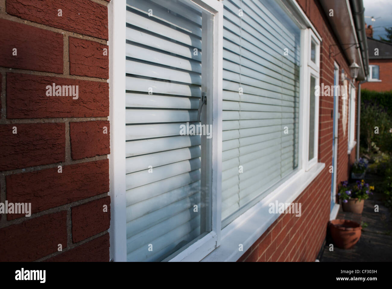 White framed window with white blind in brick wall at front of house at ...