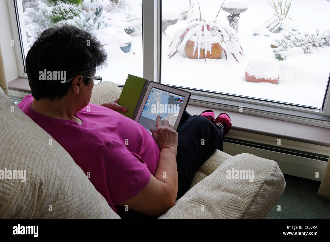 Woman home alone using Apple iPad tablet computer sitting in armchair ...