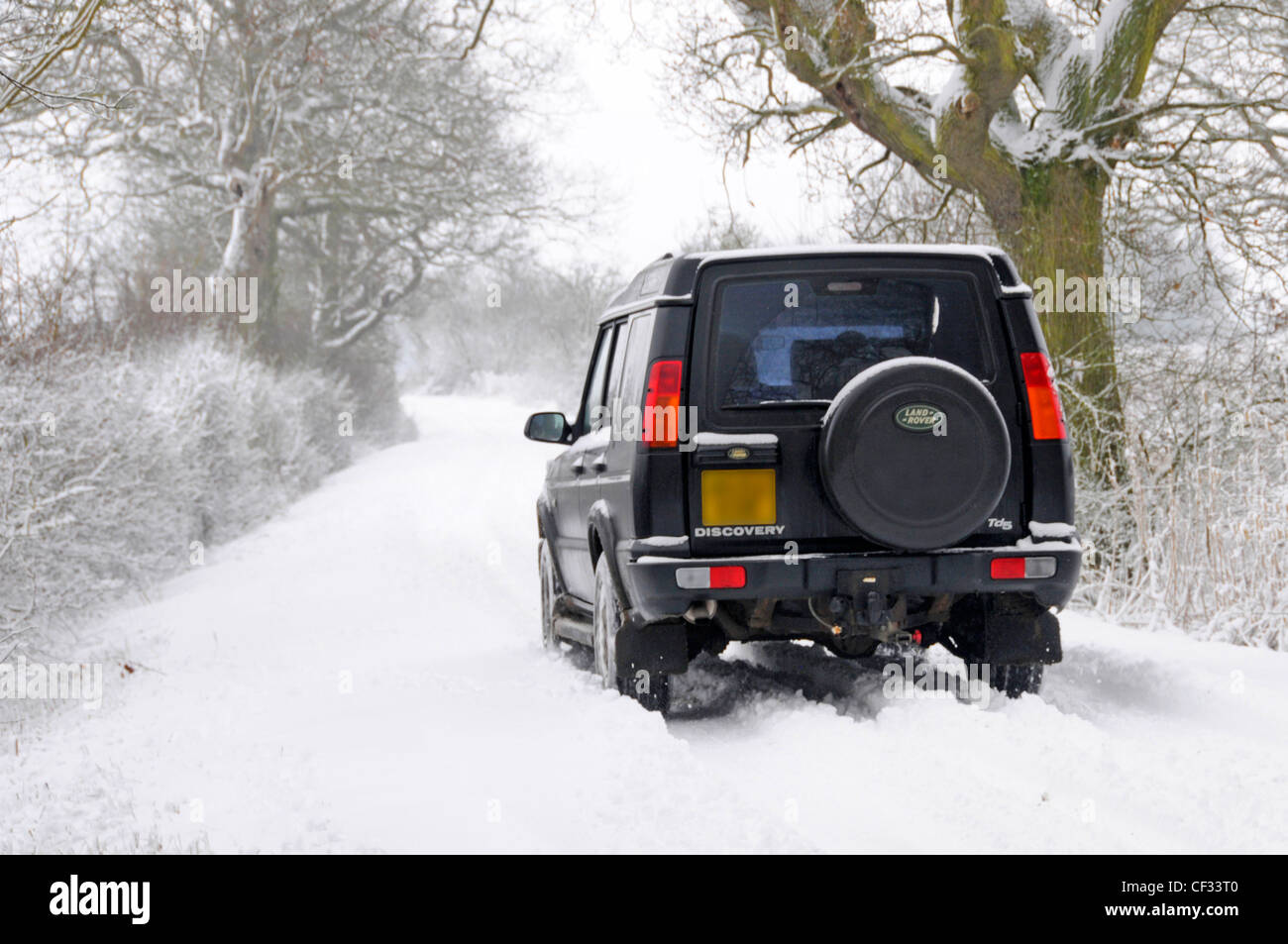 Land Rover Discovery being driven along snow covered country lane ...