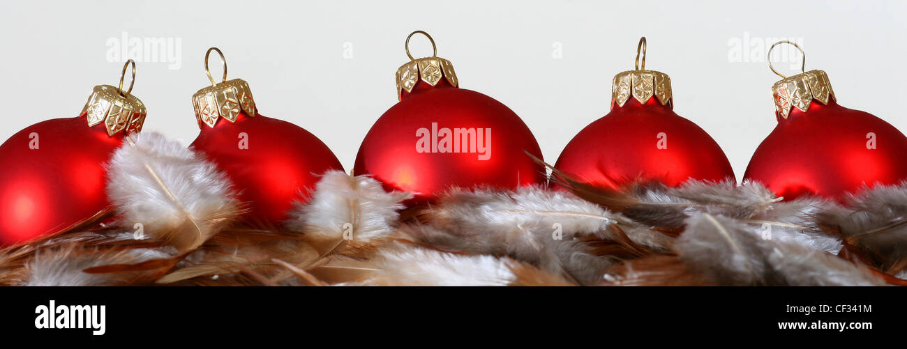 A line of metallic red baubles, with feathers in front of them Stock ...