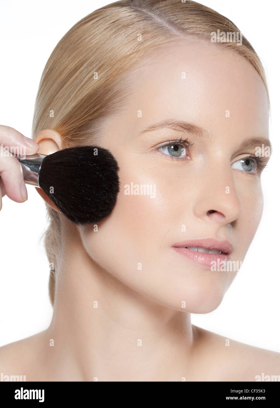 Female with blonde hair off her face, wearing subtle make up, applying ...