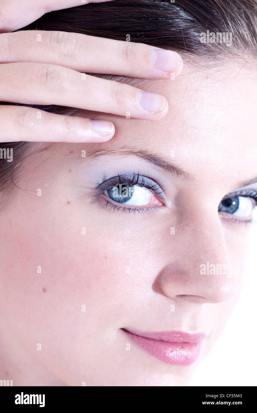 Female with brunette hair off her face, touching forehead with fingers ...