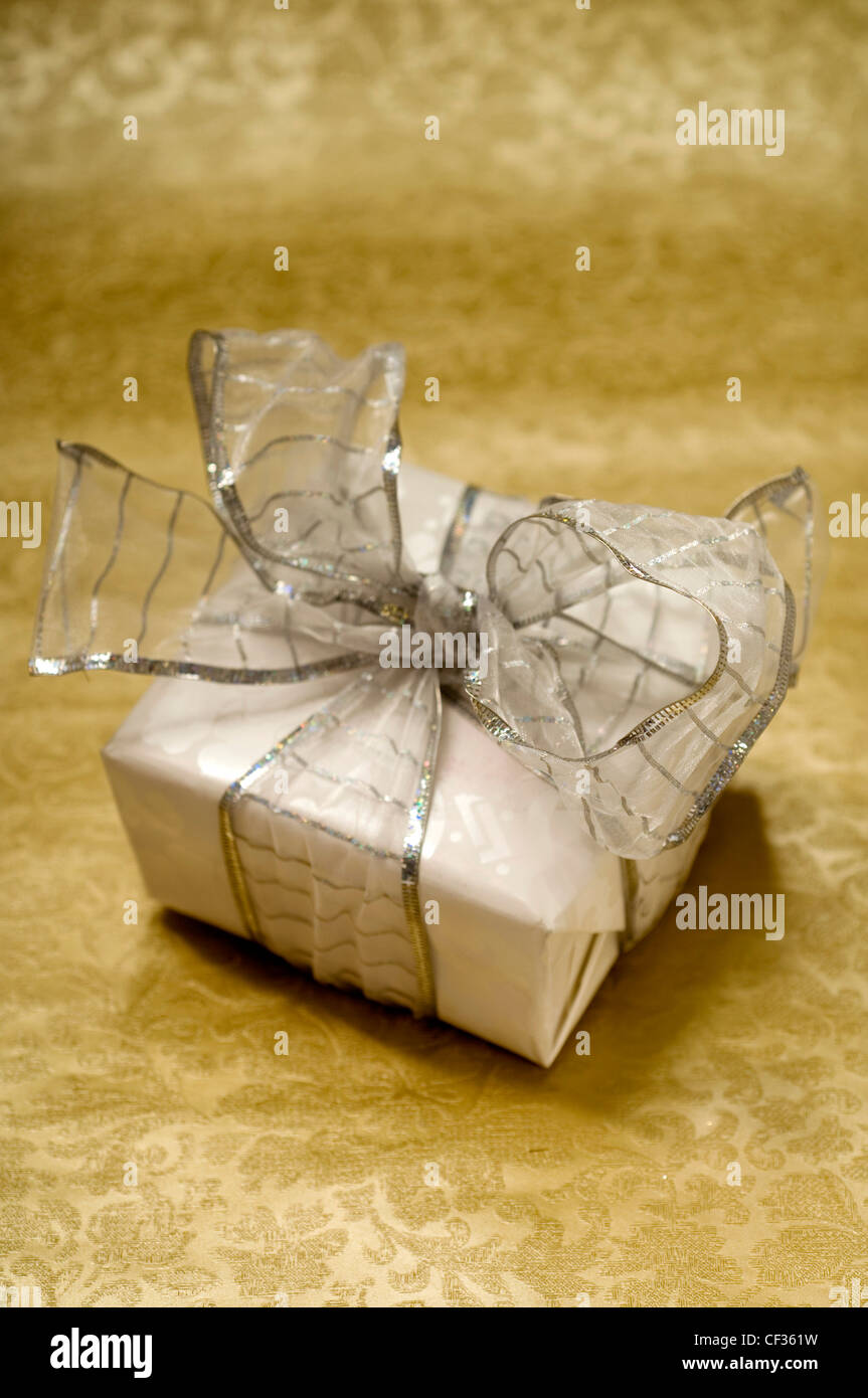 Small Christmas present wrapped with cream paper with wide sheer silver ...