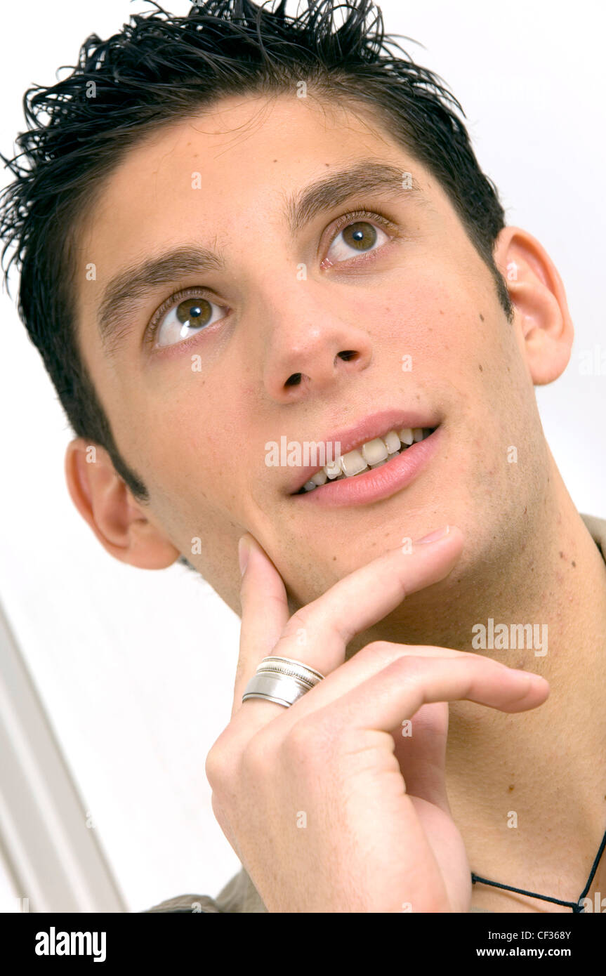 Male with short brunette hair, holding chin in hand and half smiling ...