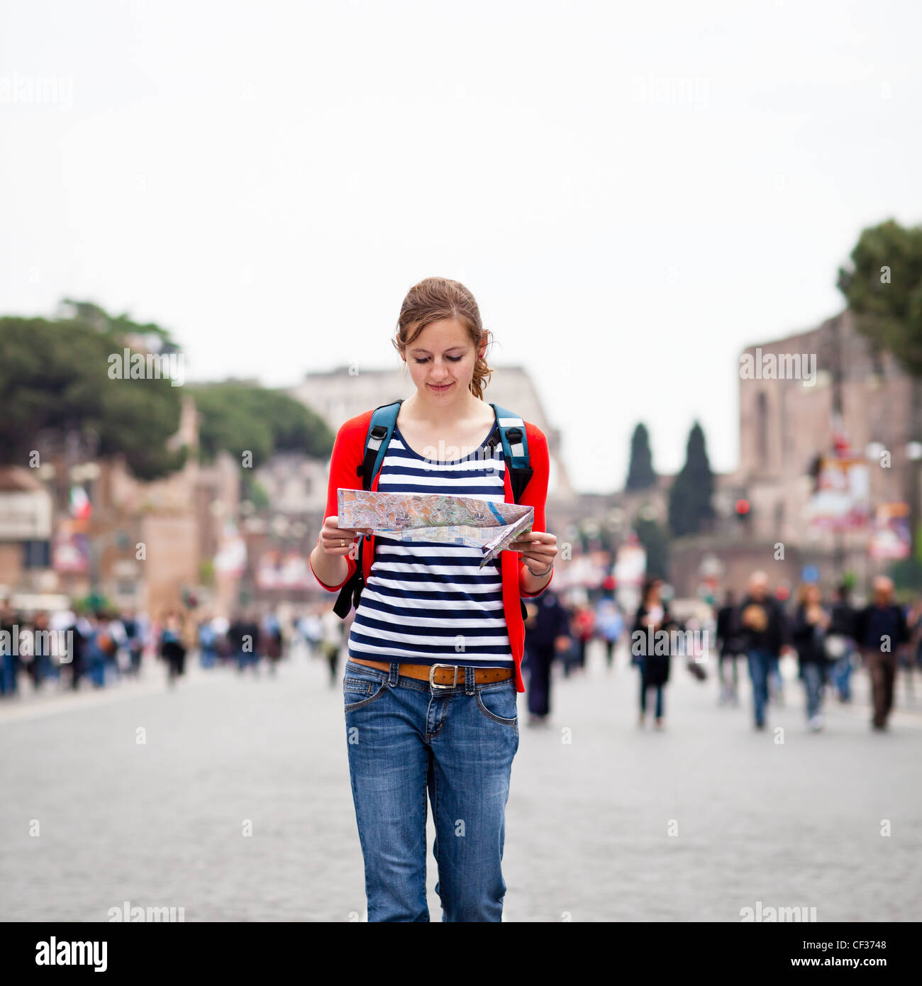 Pretty young female tourist walking along the Via del Fori Imperiali ...