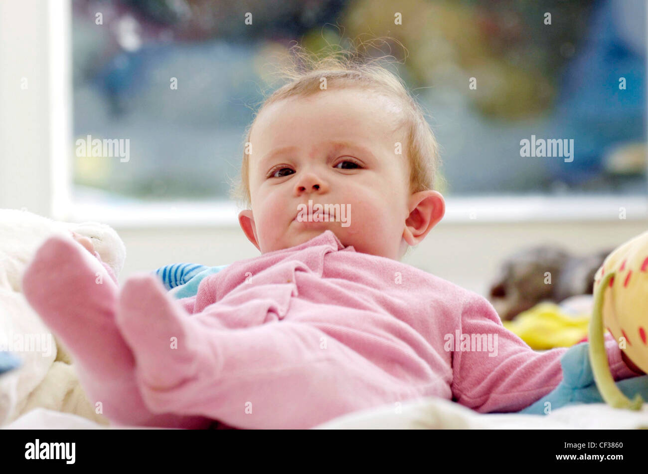 Female baby, months old, wearing a pink babygro, lying on her back ...