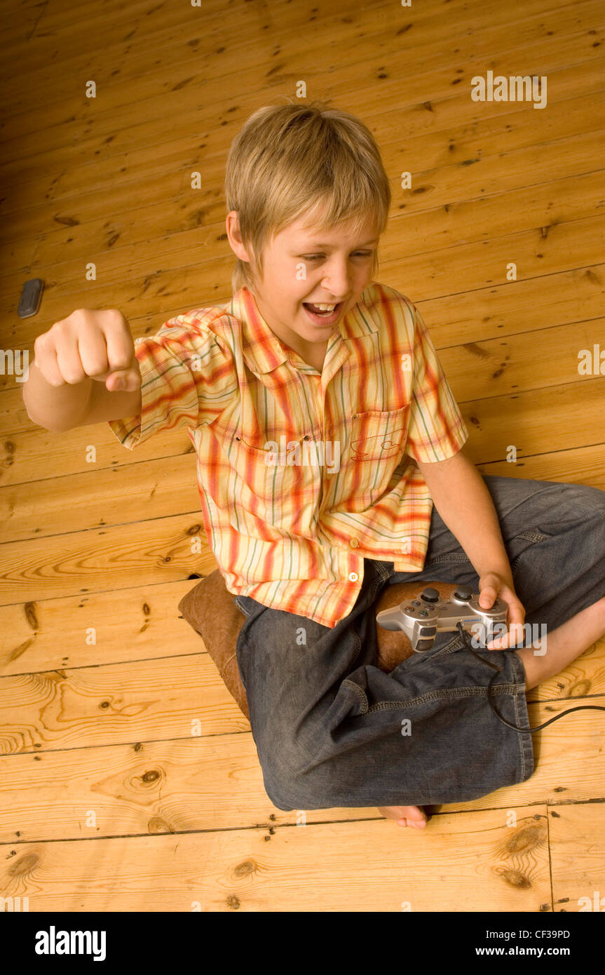 A young male playing on a computer game with a control pad, punching ...