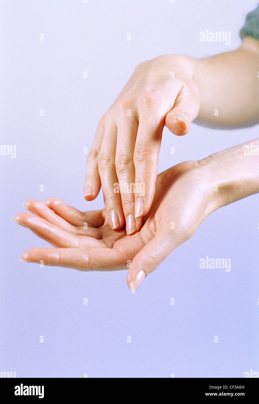 Female rubbing her fingertips on the palm of her other hand Stock Photo ...
