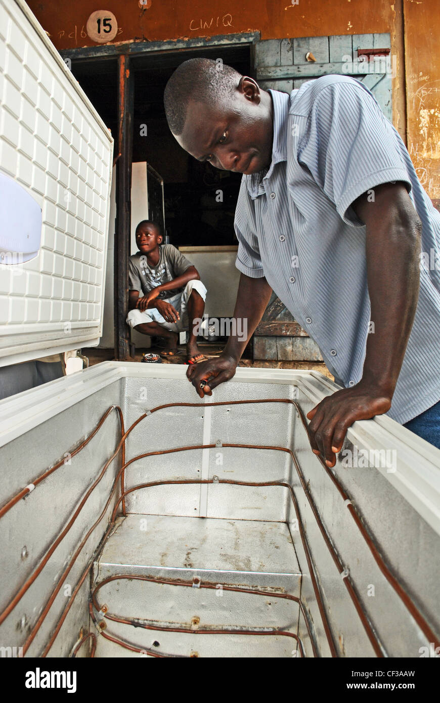 An electrician works on a broken freezer in Bo, Sierra Leone Stock ...