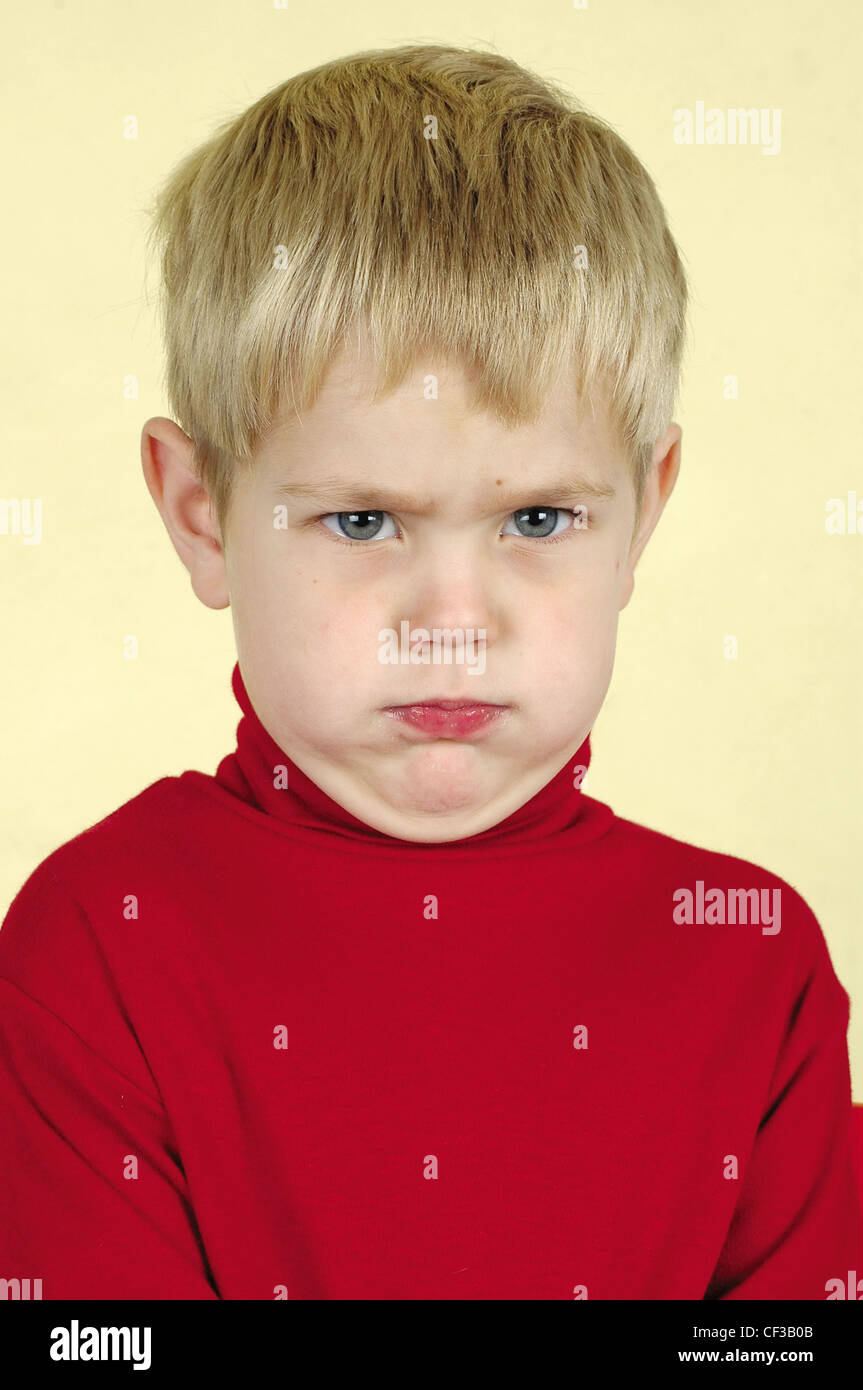 Blonde three year old boy wearing red turtle neck jumper making a ...