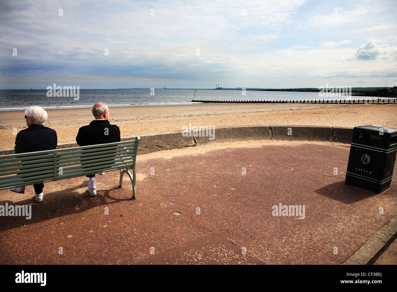 A couple sitting on a bench enjoying the calm of Portobello beach in ...