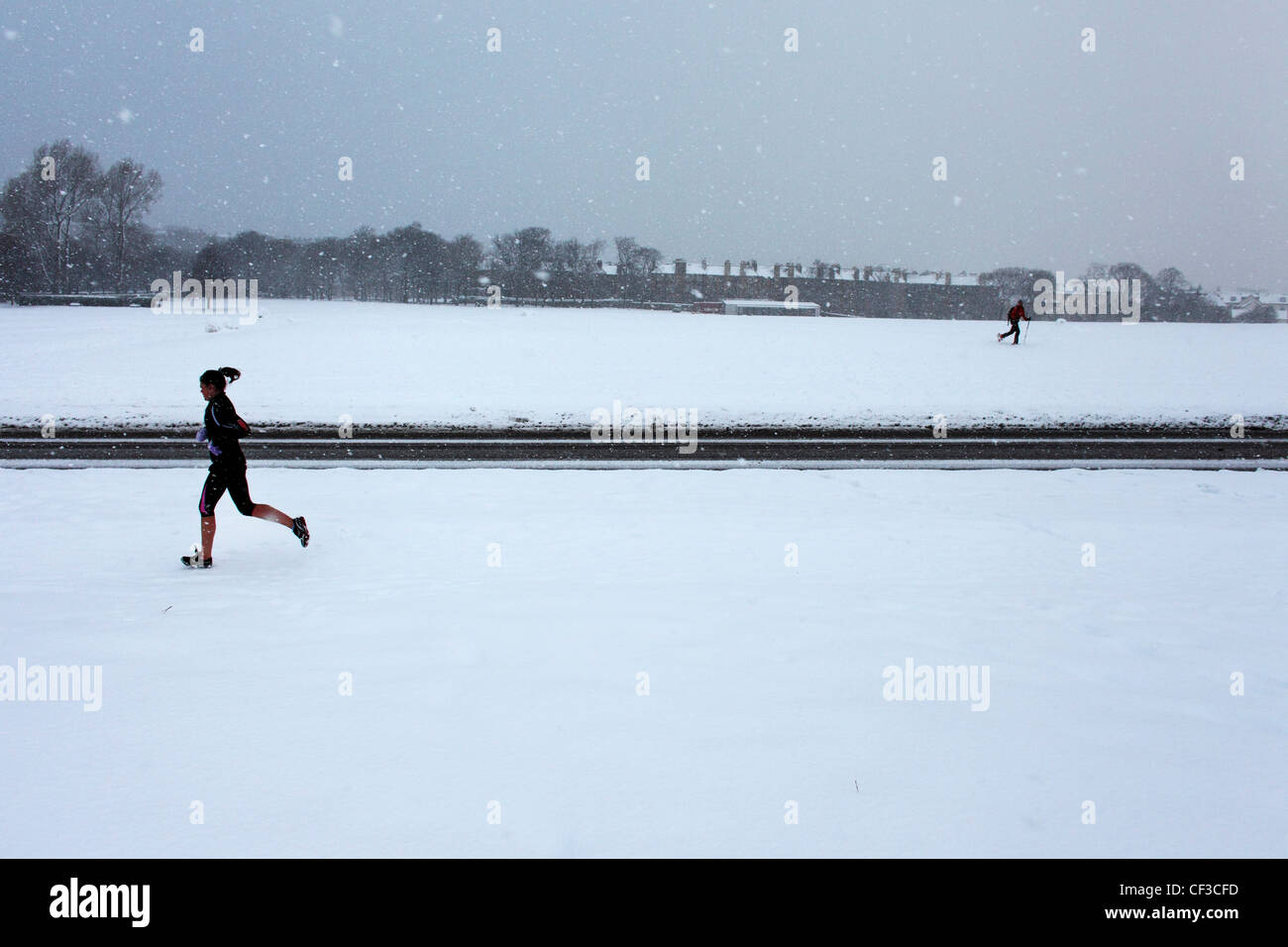 A woman running during a snow storm in Holyrood Park Stock Photo - Alamy