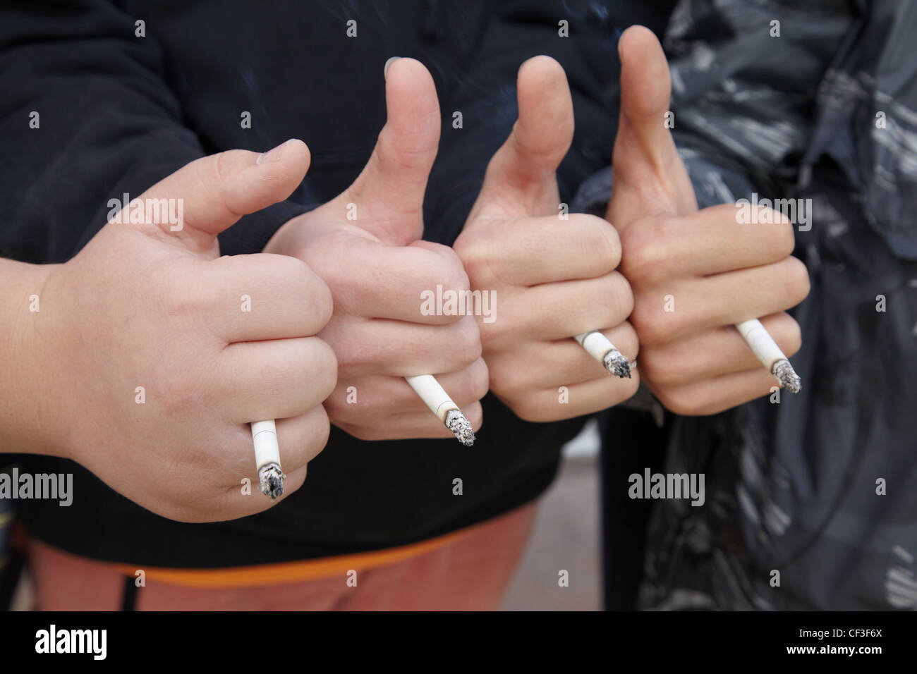 four hands of teens with thumbs up gestures and cigarettes Stock Photo ...