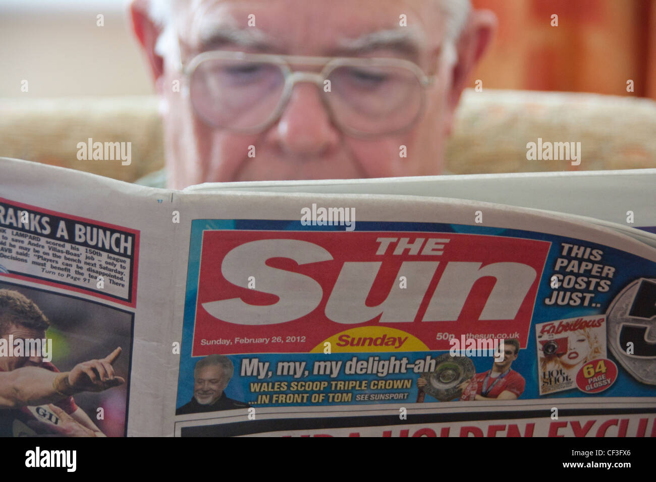 Man reading first edition of The Sun on Sunday tabloid newspaper ...