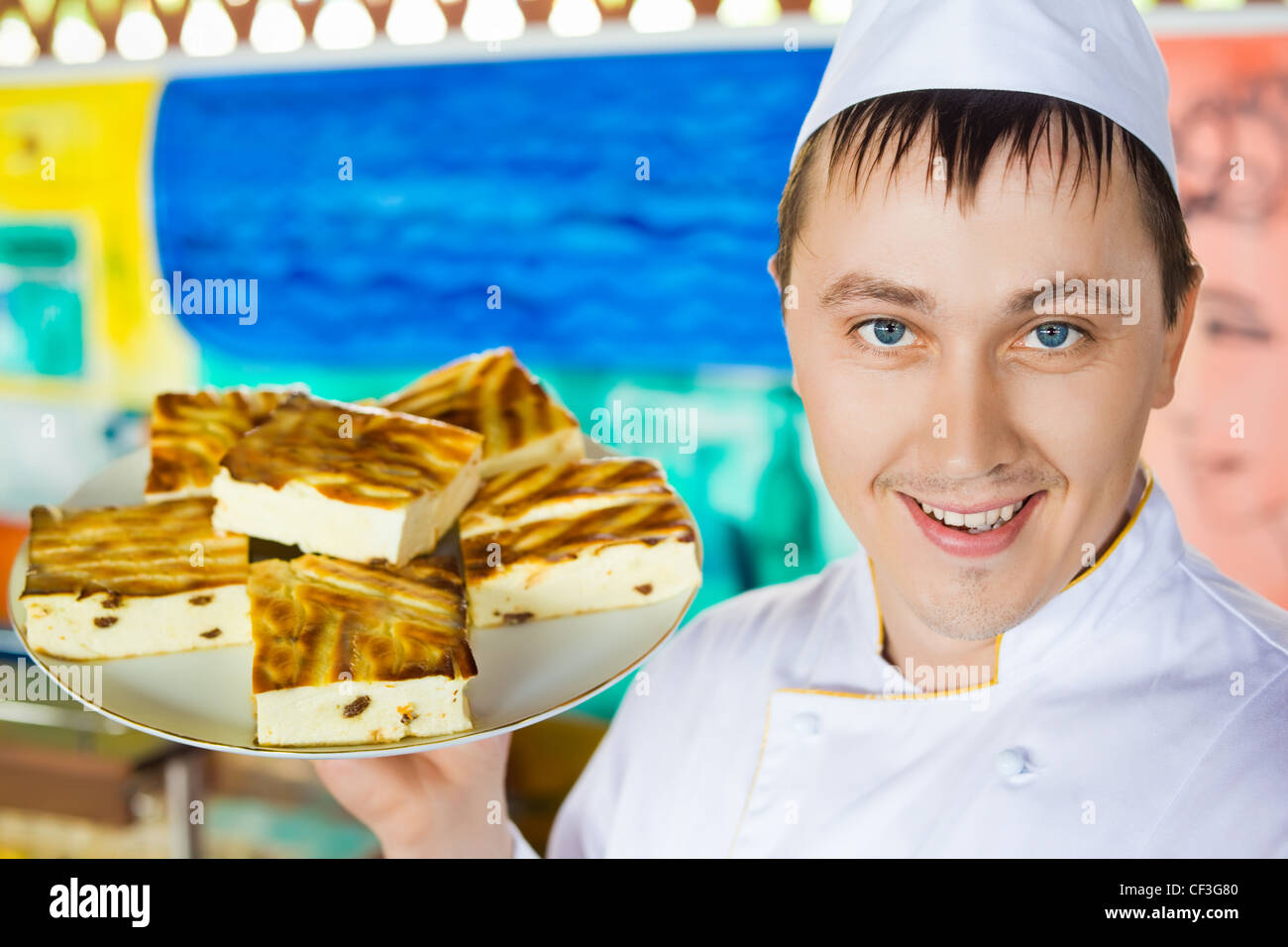 cheerful cook in uniform holding cheese baked pudding on dish Stock ...