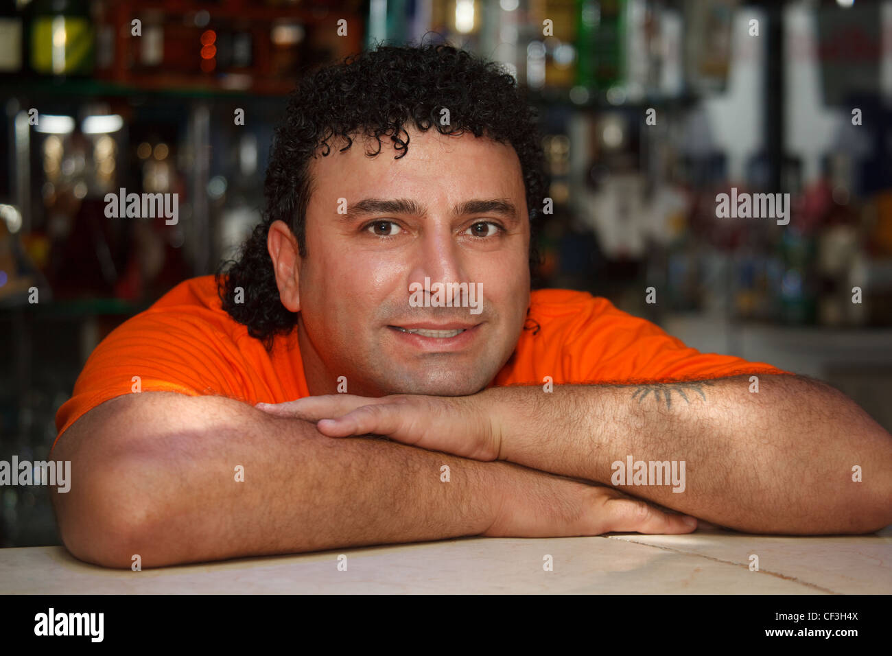 Bartender sits at bar. Smiling man against shelves with bottles Stock ...