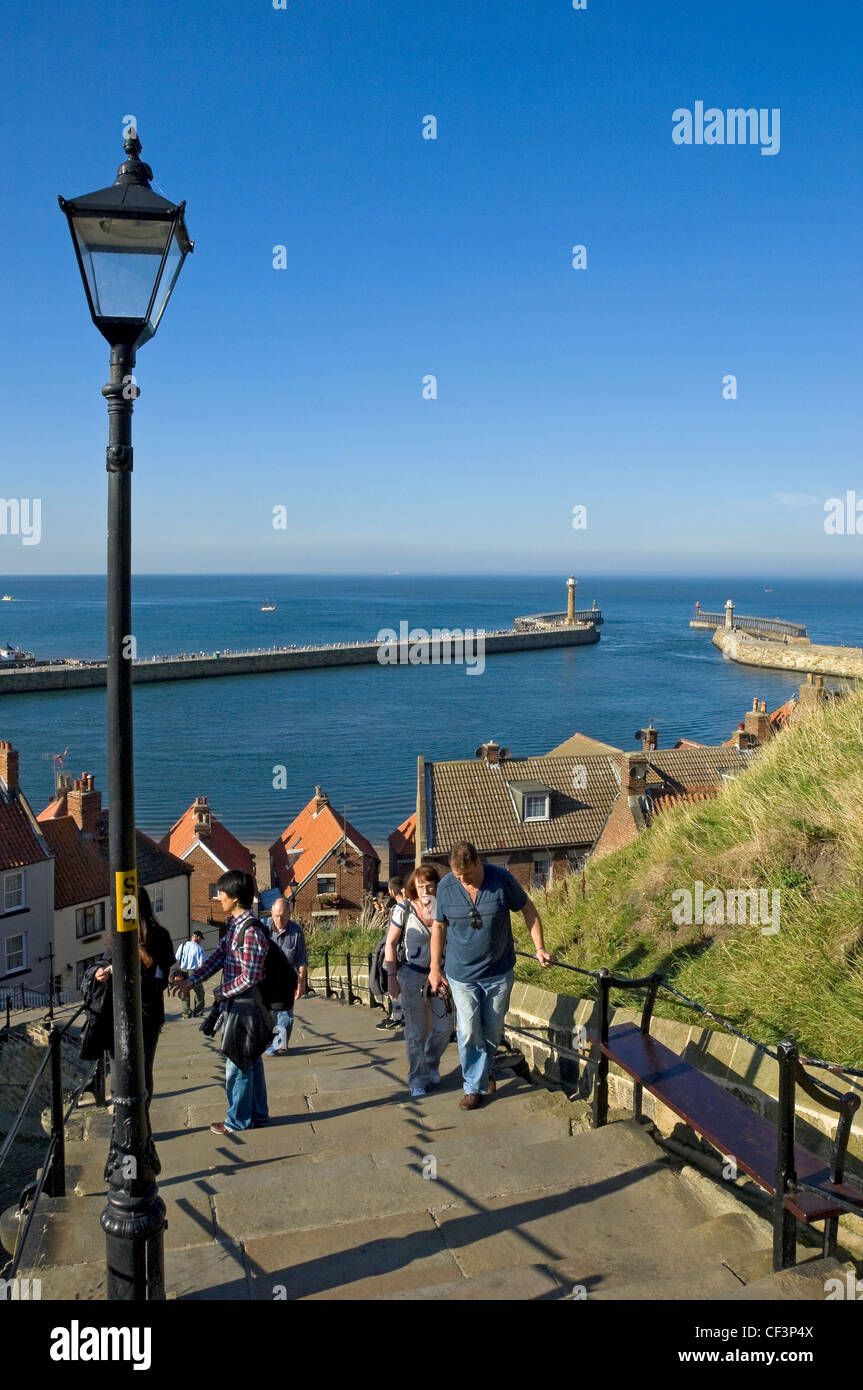 People walking up Whitby's famous '199 steps' with the harbour and Pier ...