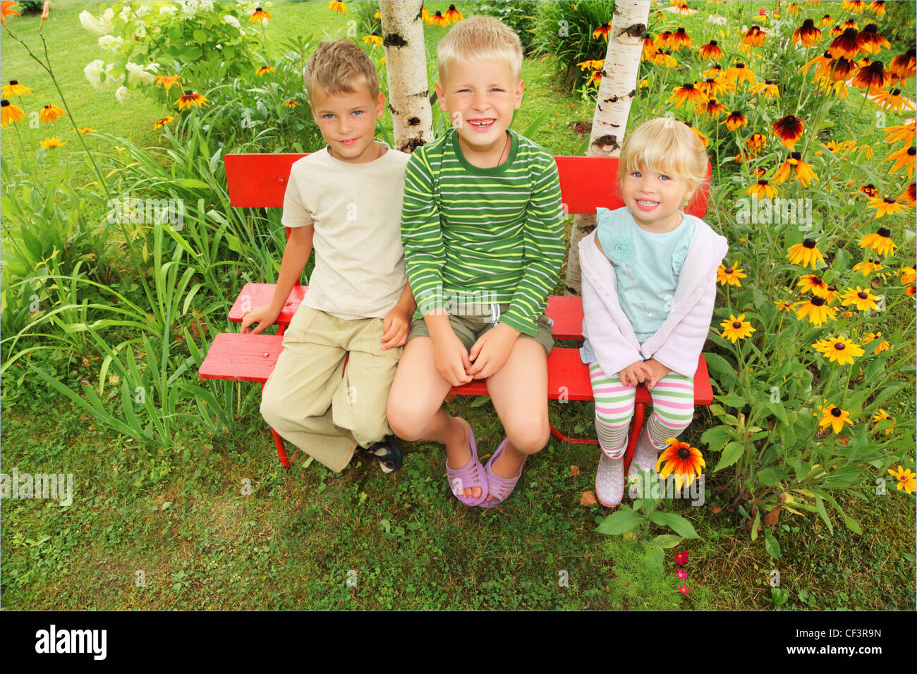 Children sitting on bench in garden Stock Photo - Alamy