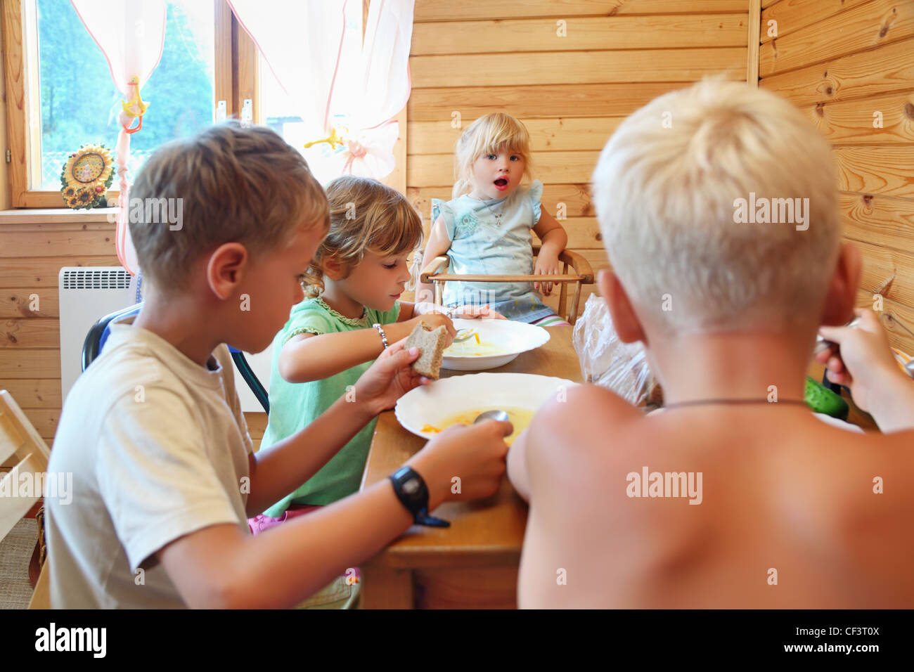 Children having dinner behind table Stock Photo - Alamy