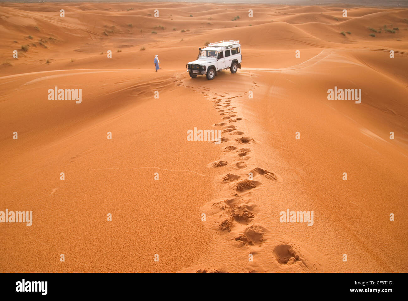 A Moroccan driver standing beside his tour jeep in the Moroccan desert ...