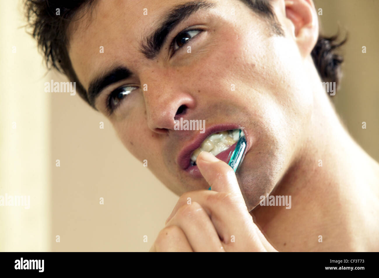 Male dark brown hair brushing teeth green toothbrush, head tilted ...
