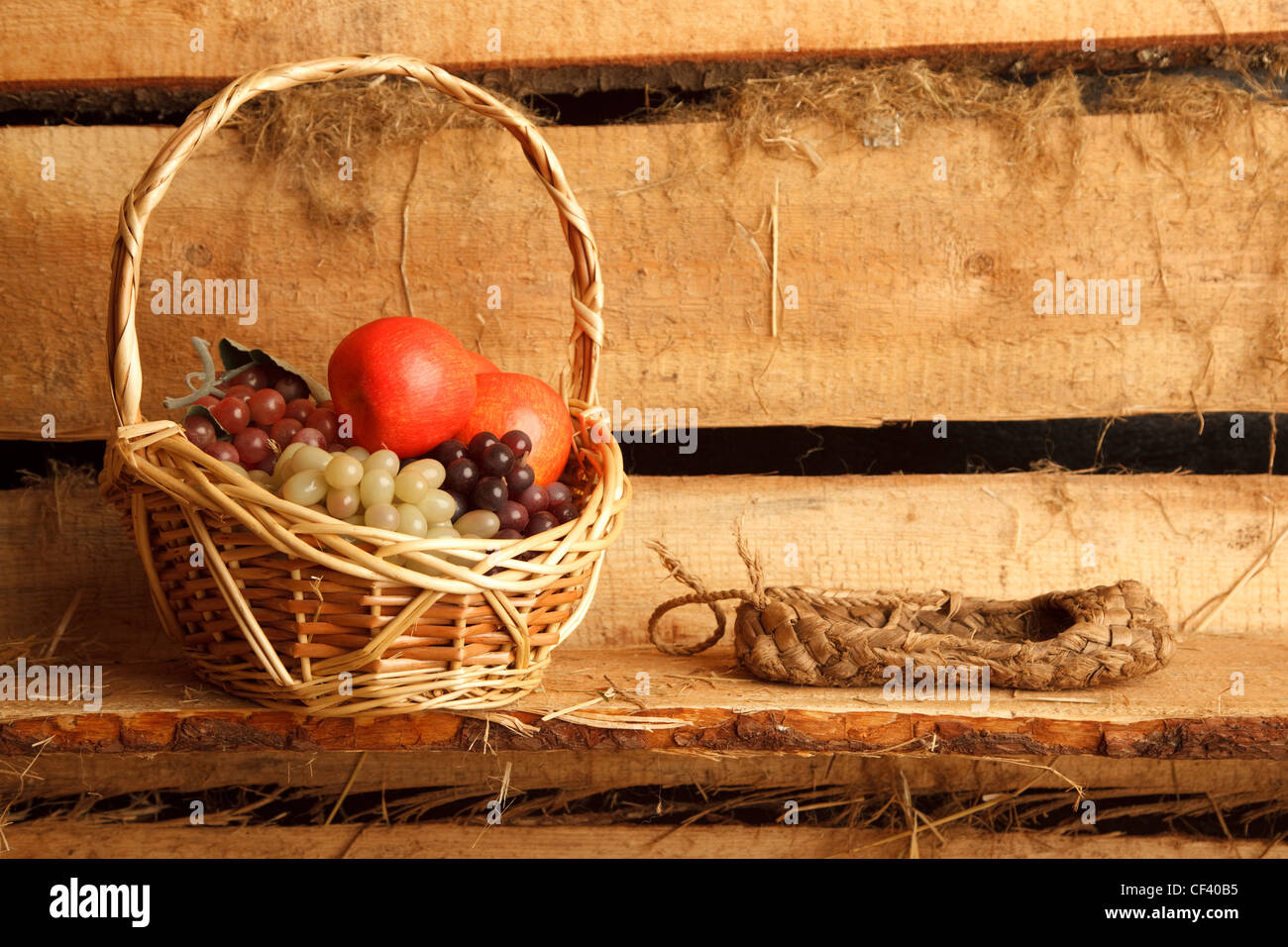 Rural still life. Basket of grapes and apples, and bast shoes on ...