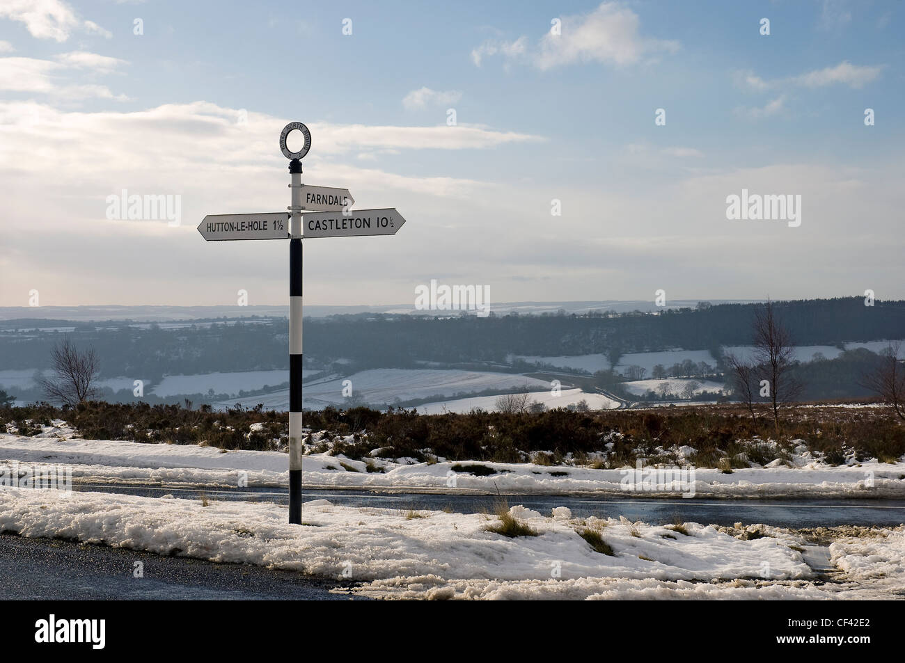Snow surrounds a signpost next to a road on the North York Moors Stock ...