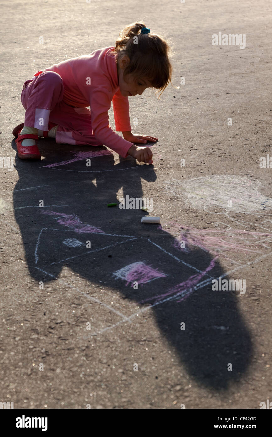 girl sits concrete asphalt square road girl draws painting line sun ...