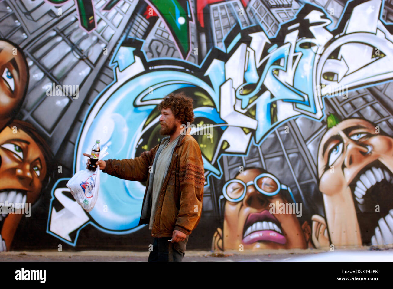 A homeless man in front of some graffiti. The word 'graffiti' is the ...