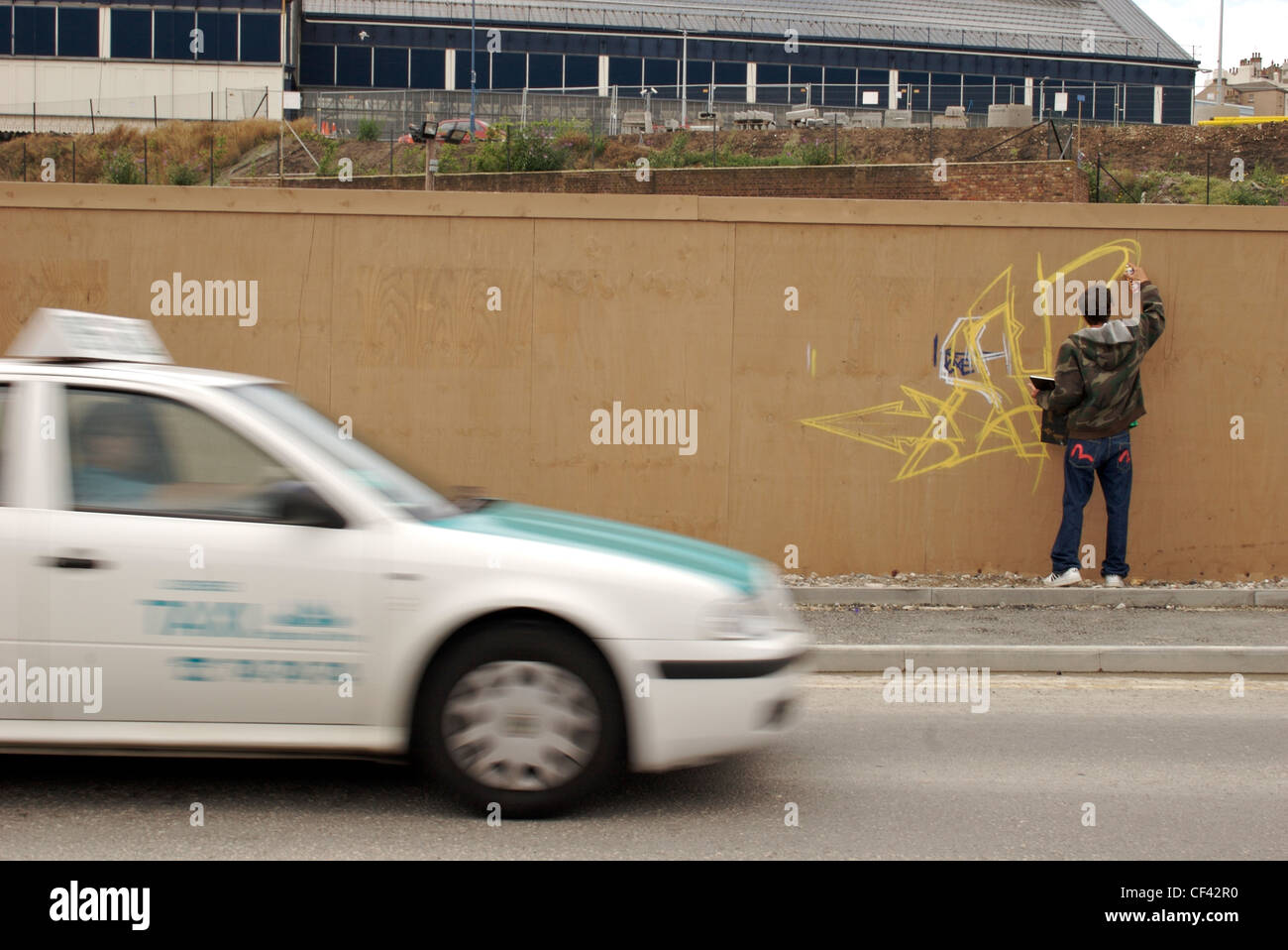 A graffiti artist sketches as a taxi drives past. Graffiti artist ...